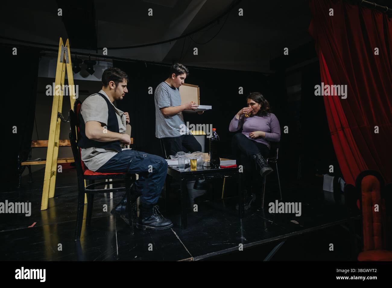 Young actors rehearsing a scene on a theater stage with props and ...