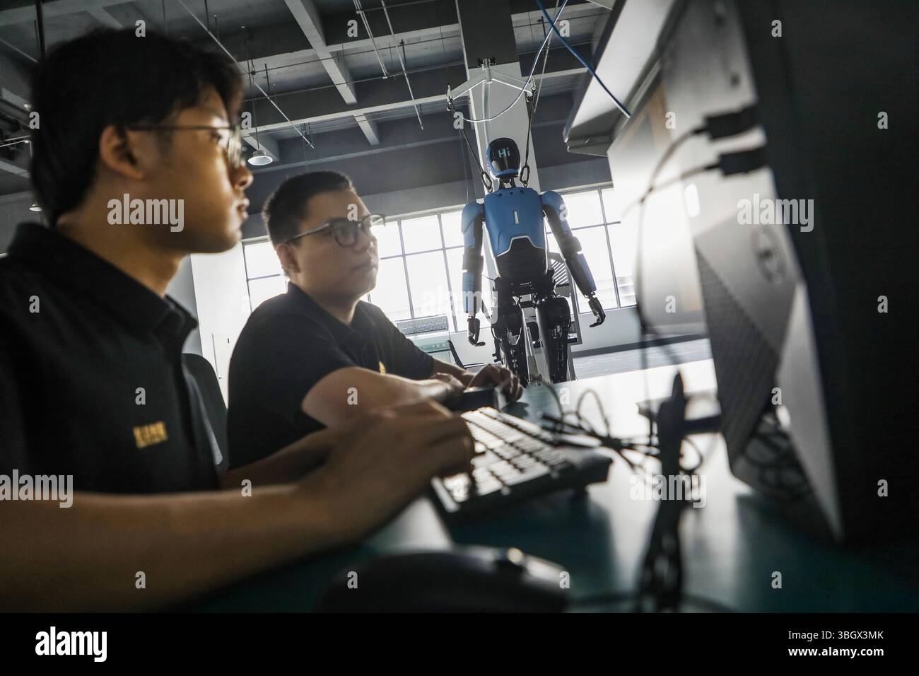 Engineers work at a lab where over 40 humanoid robots are under ...