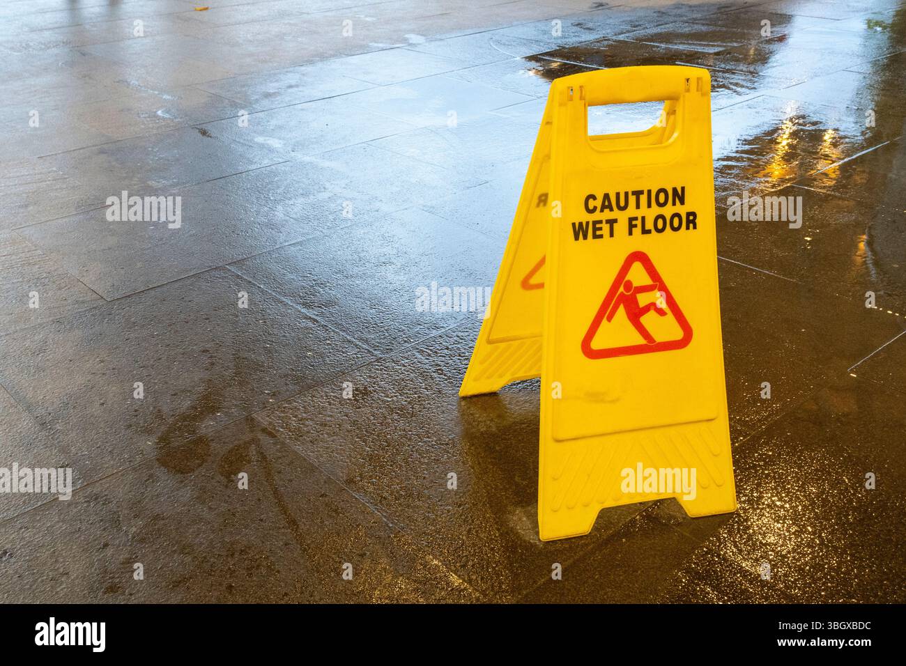 Yellow caution sign is on the ground. The sign warns people that the ...