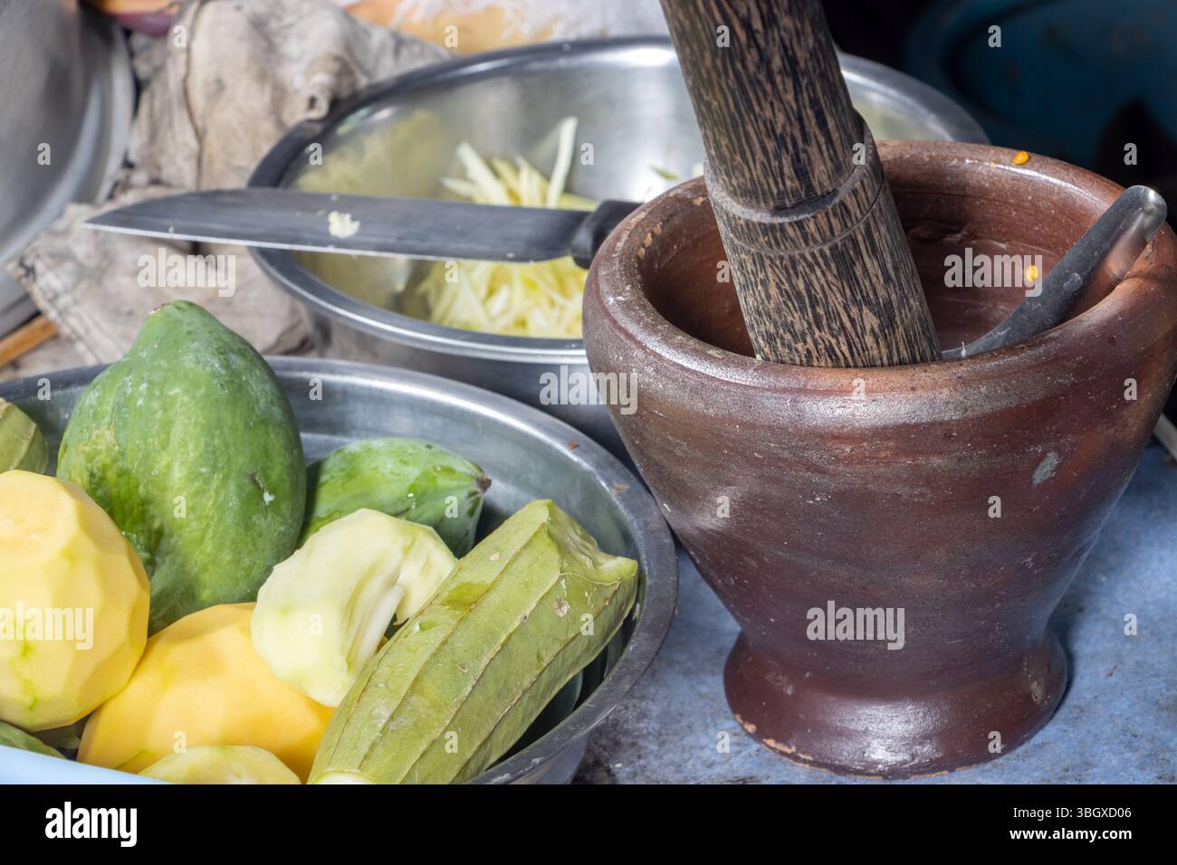A traditional Thai cooking setup featuring fresh vegetables, a mortar ...