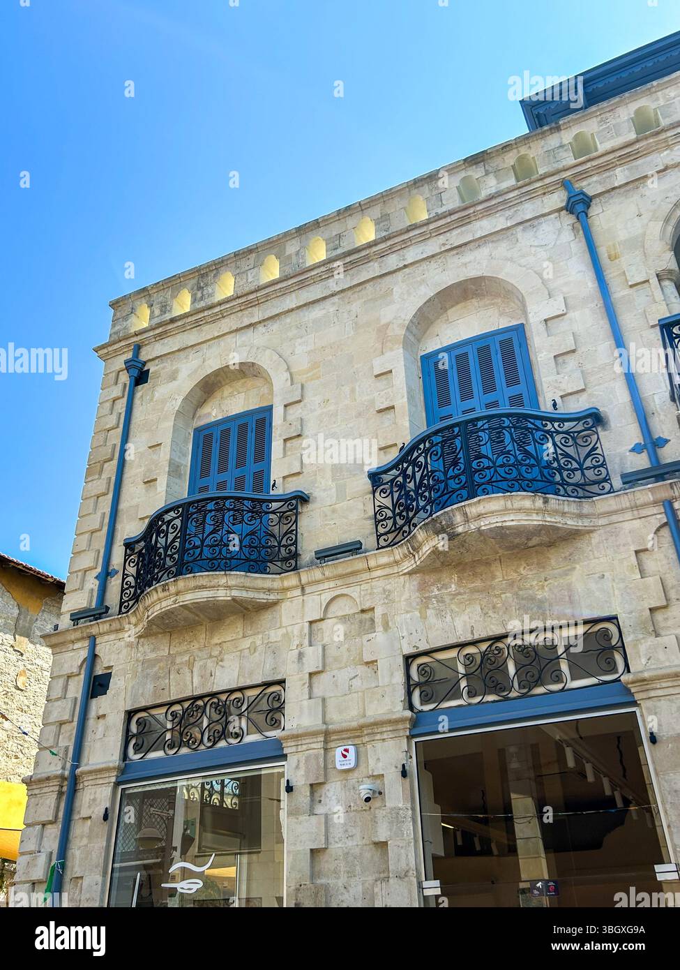 Historic stone building with blue shutters and wrought iron balconies ...