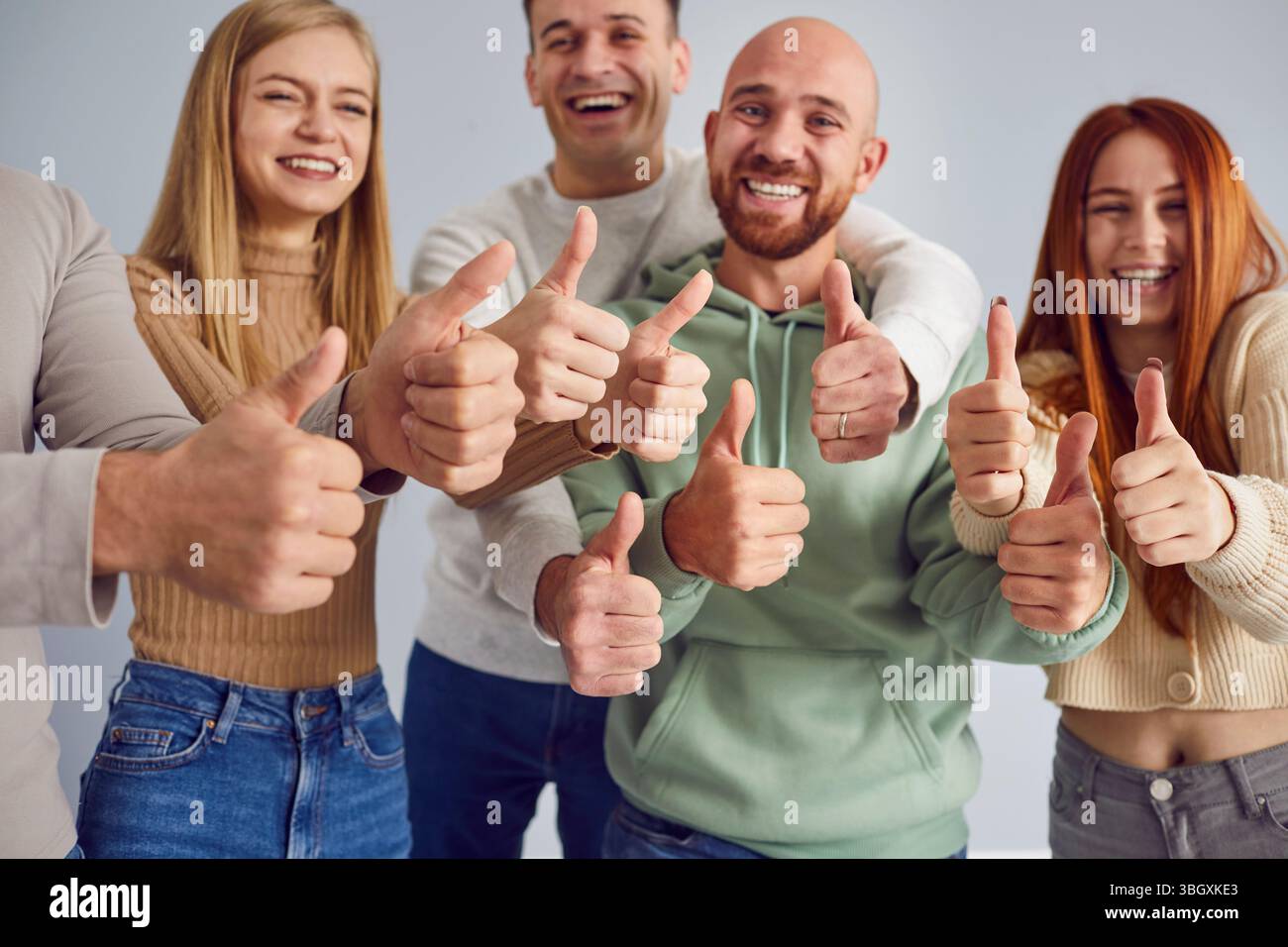 Group of young happy people showing thumb up gesture of approval ...