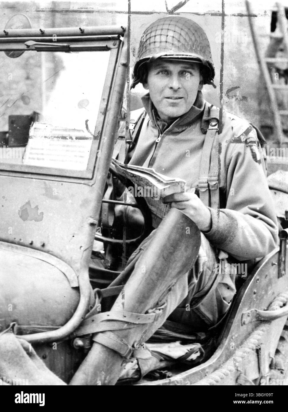 Seated in a jeep, Brigadier General Maxwell Taylor studies a map at an ...