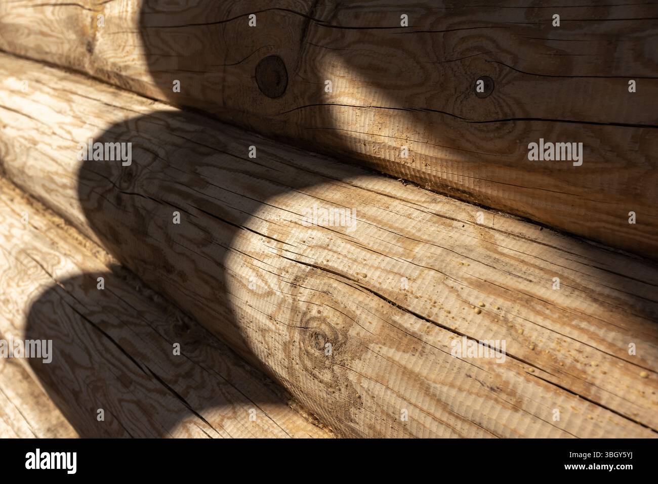 Close-up of a wooden log wall surface with sunlight creating dramatic ...