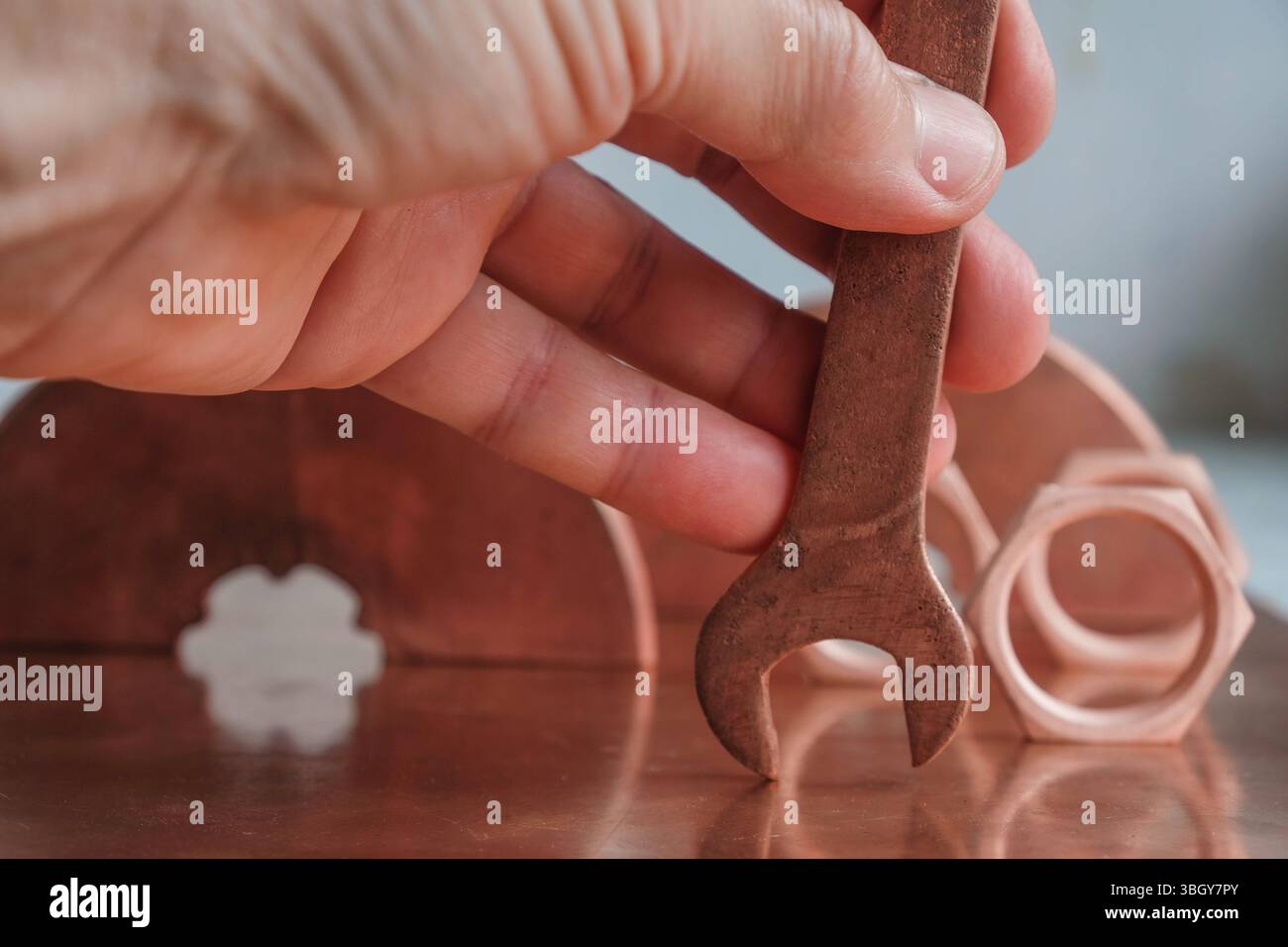 Copper wrench in a female hand on a background of copper tools ...