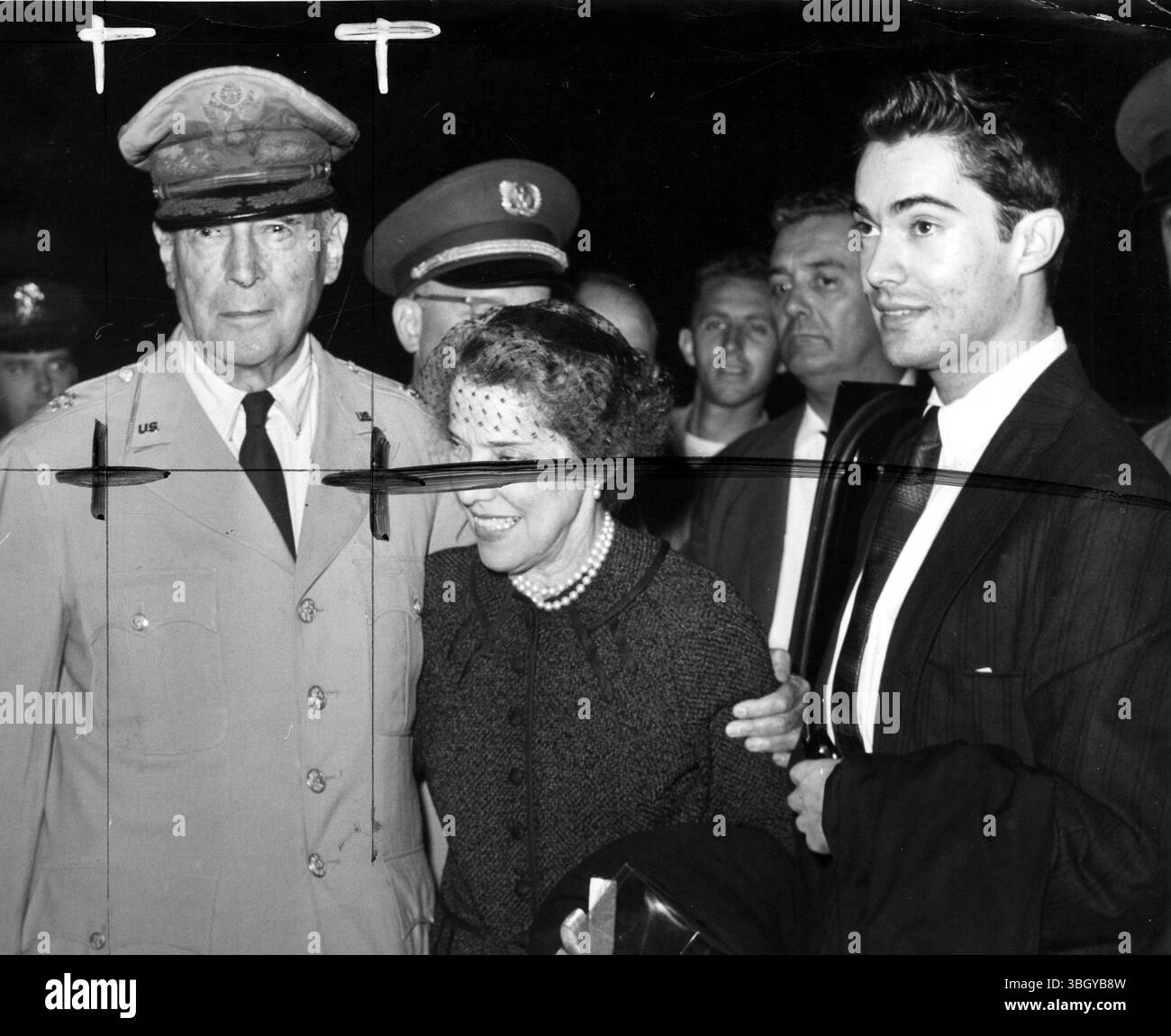 General Douglas MacArthur (left) holds his wife, Jean, as his son, Arthur (right) looks on at ...