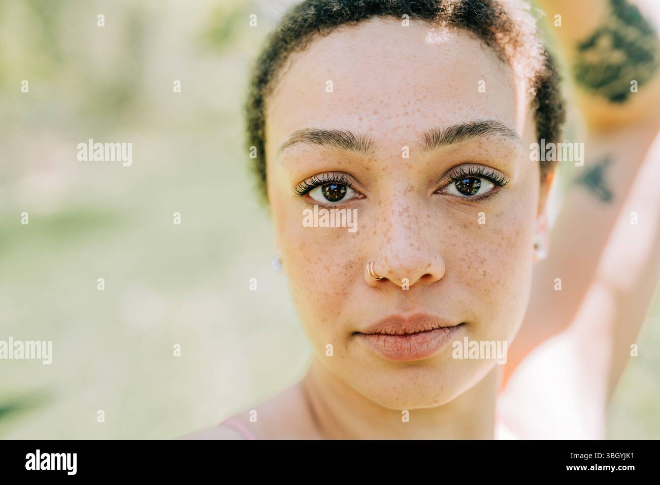 Freckled woman looks forward with soft focus and green backdrop Stock ...