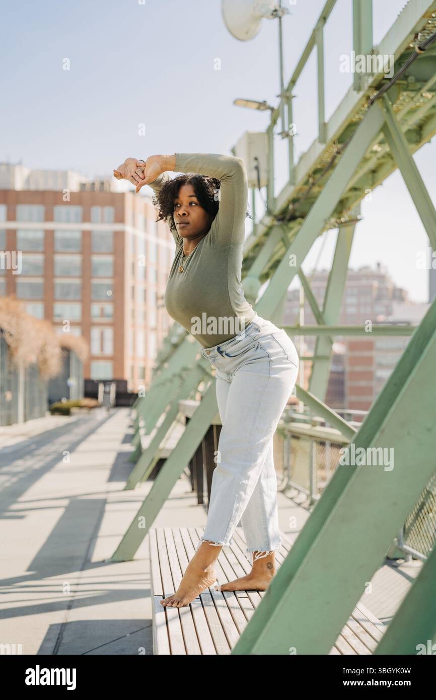 Woman standing barefoot on bench in a graceful dance pose Stock Photo ...