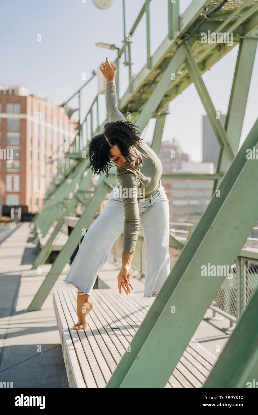 Woman in green top leans gracefully in a dance pose on a bench Stock ...