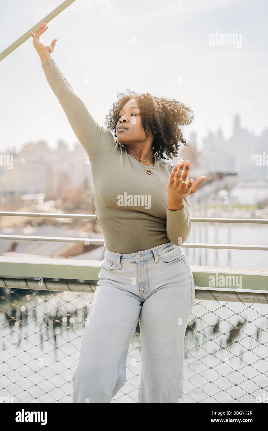 Dancer poses expressively with one arm raised near waterfront Stock ...