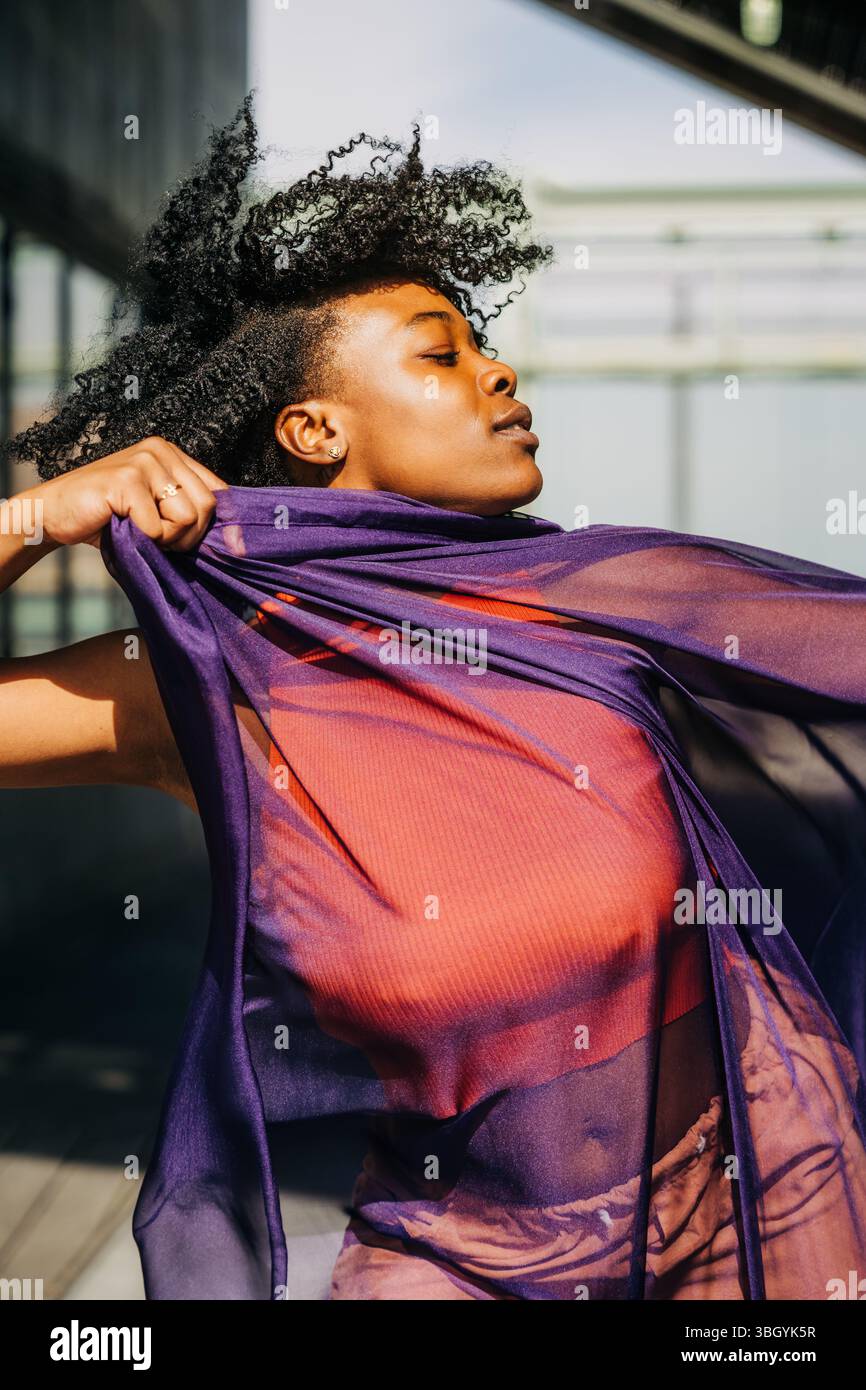 Side view of woman in sheer purple fabric with windswept hair Stock ...