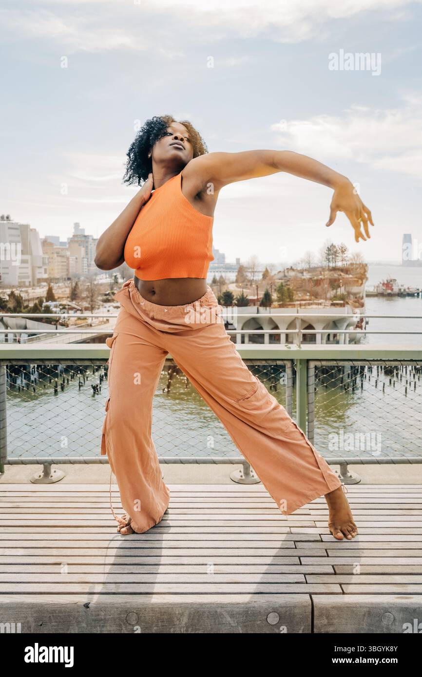 Woman striking elegant dance pose on platform above water Stock Photo ...