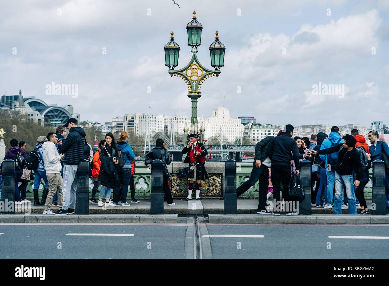 Bagpiper performs on bridge as crowd gathers around in London Stock ...