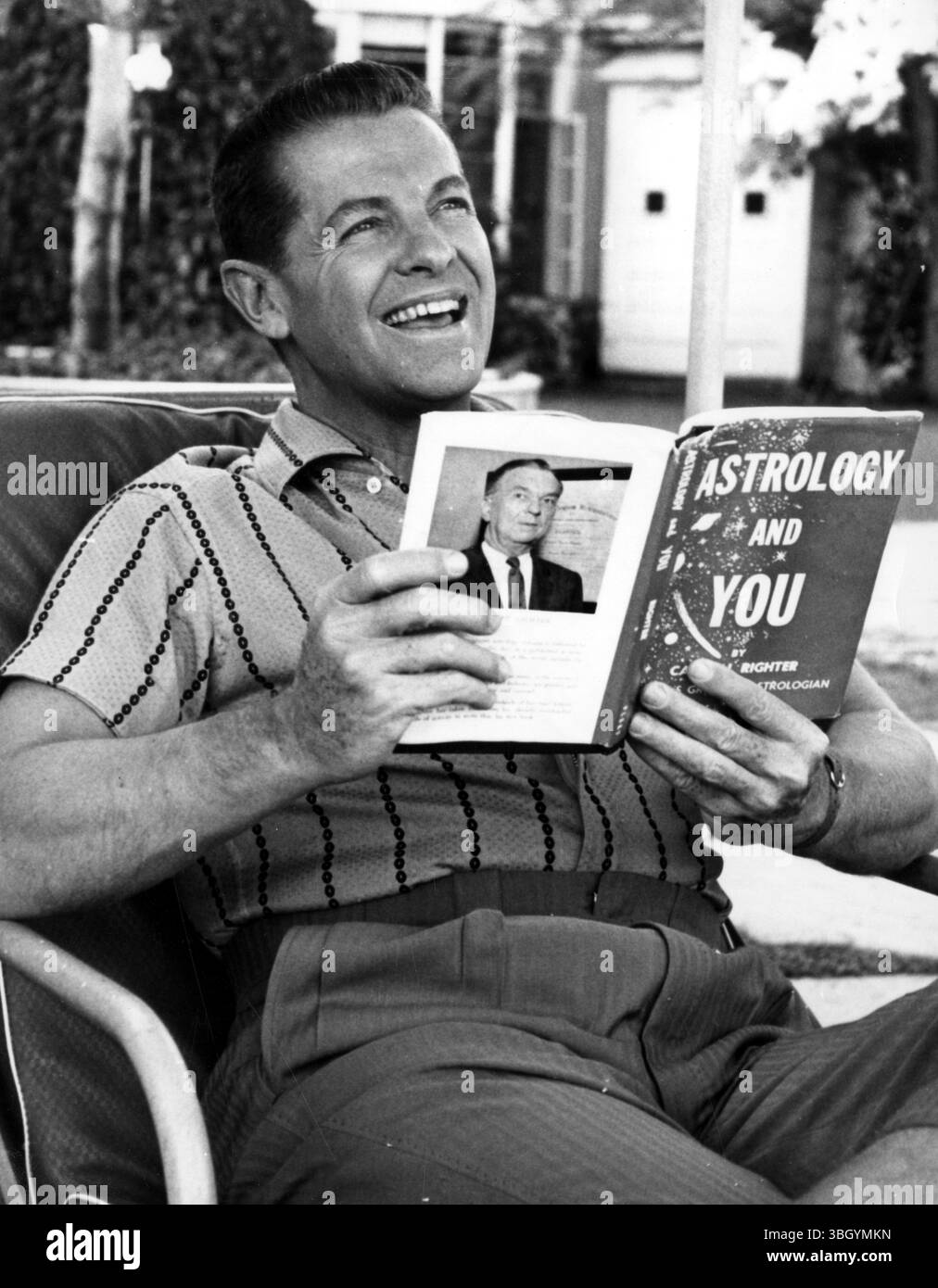 Hollywood TV star Robert Cummings sits reading an Astrology book Stock ...