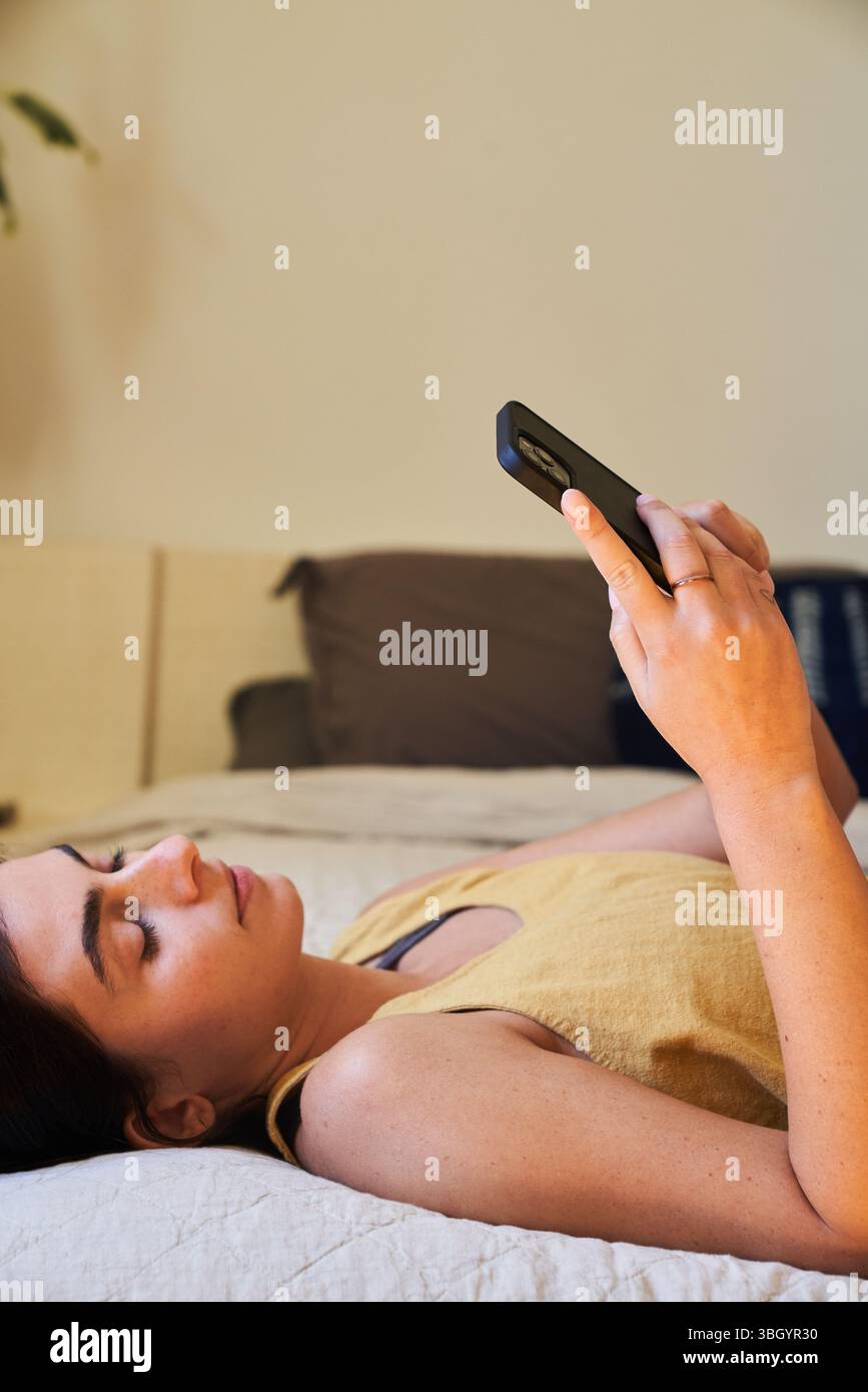 Woman laying down and looking at phone Stock Photo - Alamy