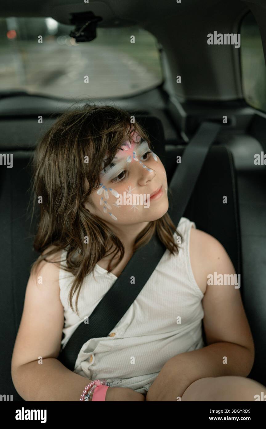 A girl with painted face sitting in the back seat of a car Stock Photo ...