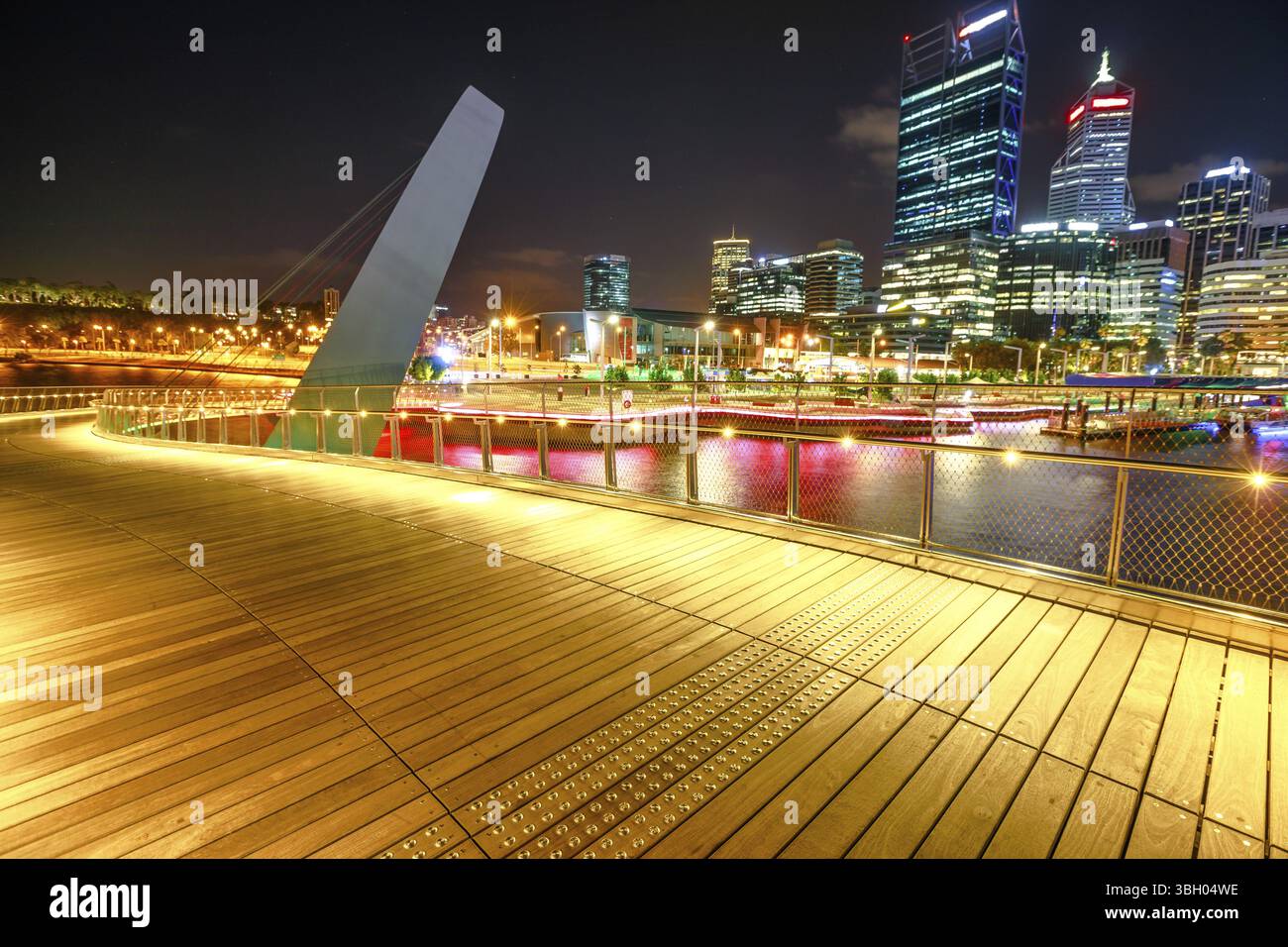 Wooden walkway of Elizabeth Quay pedestrian bridge illuminated by night ...