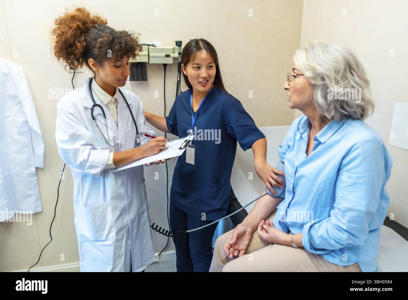 Medical professionals taking care of elderly woman's health, performing ...