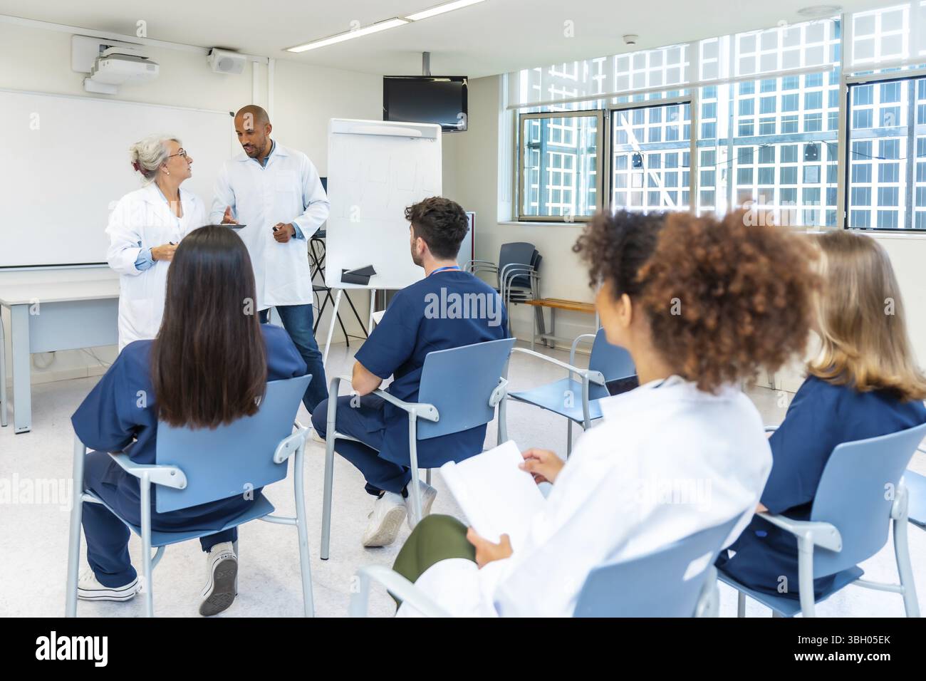 Doctors and nurses listening to senior colleagues giving presentation ...
