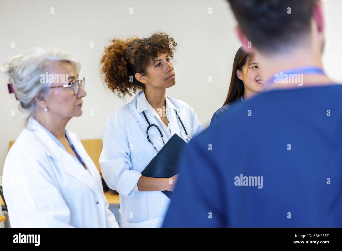 Doctors and nurses engaging in a medical staff meeting, attentively ...