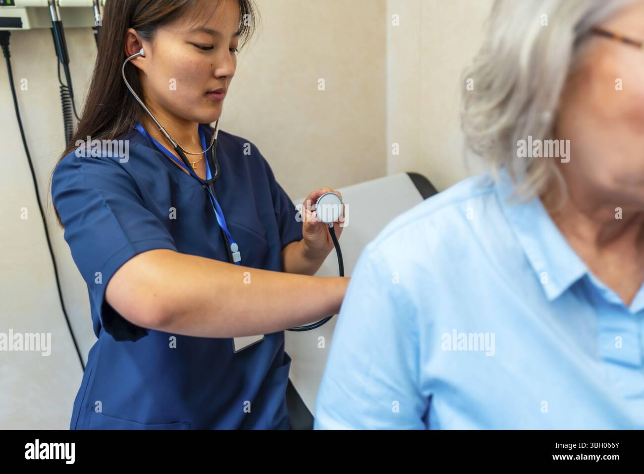 Female doctor using stethoscope examining lungs of senior patient ...