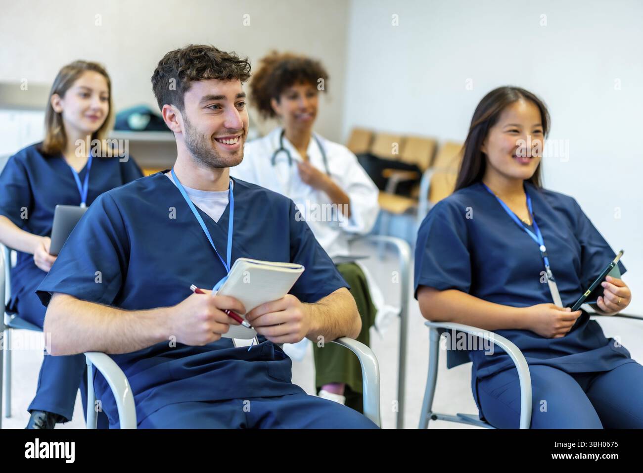 Group of smiling medical students attending a conference, taking notes ...