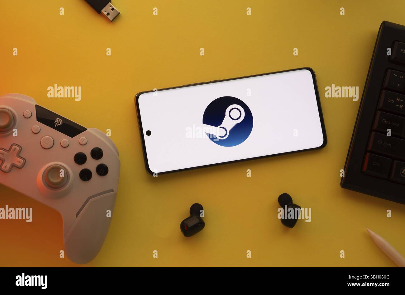 Smartphone with Steam logo, game controller, and earbuds on a yellow ...