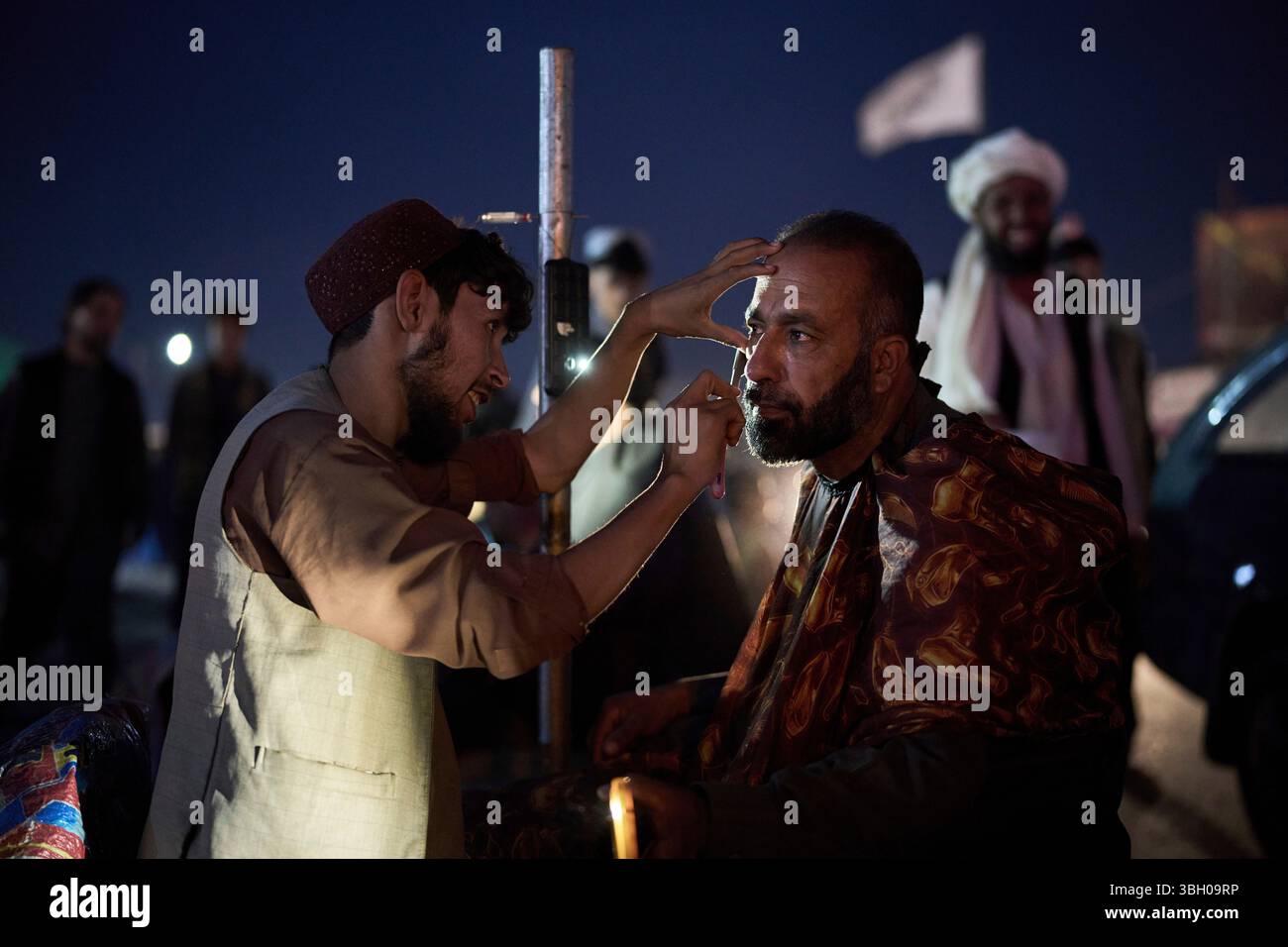 A street barber shaves a man's face in a market the day before Eid al ...
