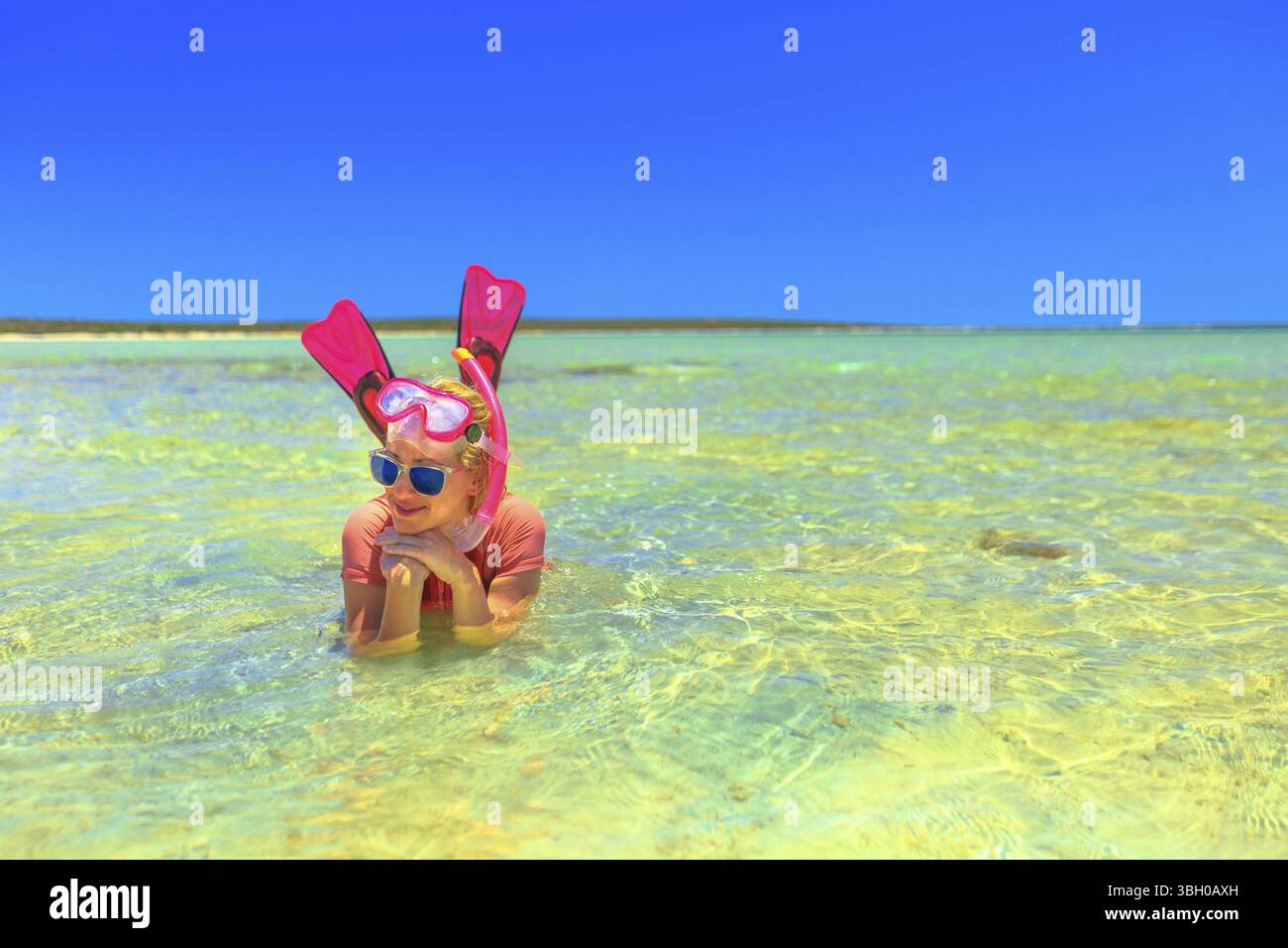 Caucasian young woman with snorkeling wetsuit, mask and fins in pink ...