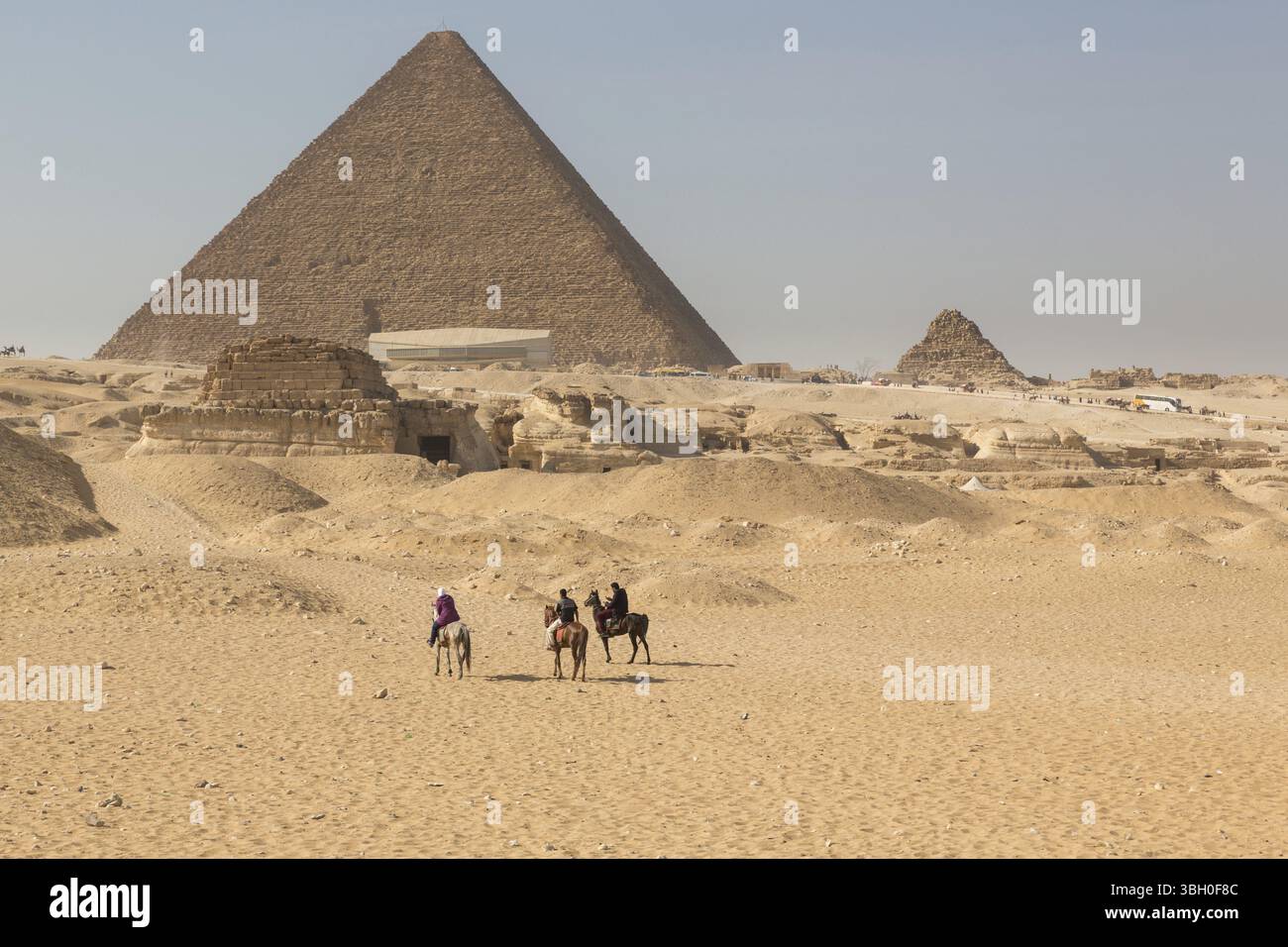 Three people riding horses in the desert by the Pyramids of Giza Stock ...