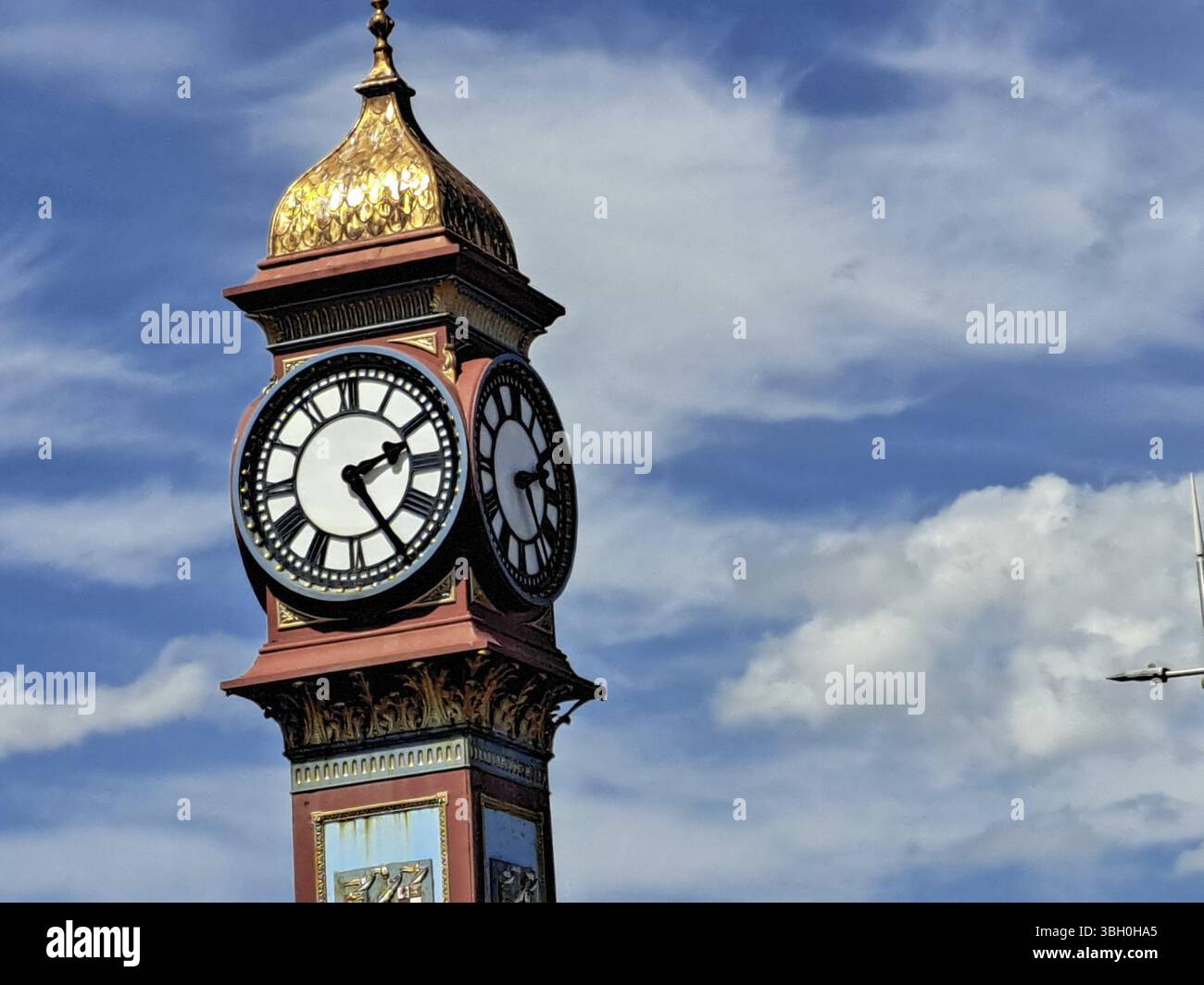 Large clock tower with golden spire in front of a white-blue sky, isle ...