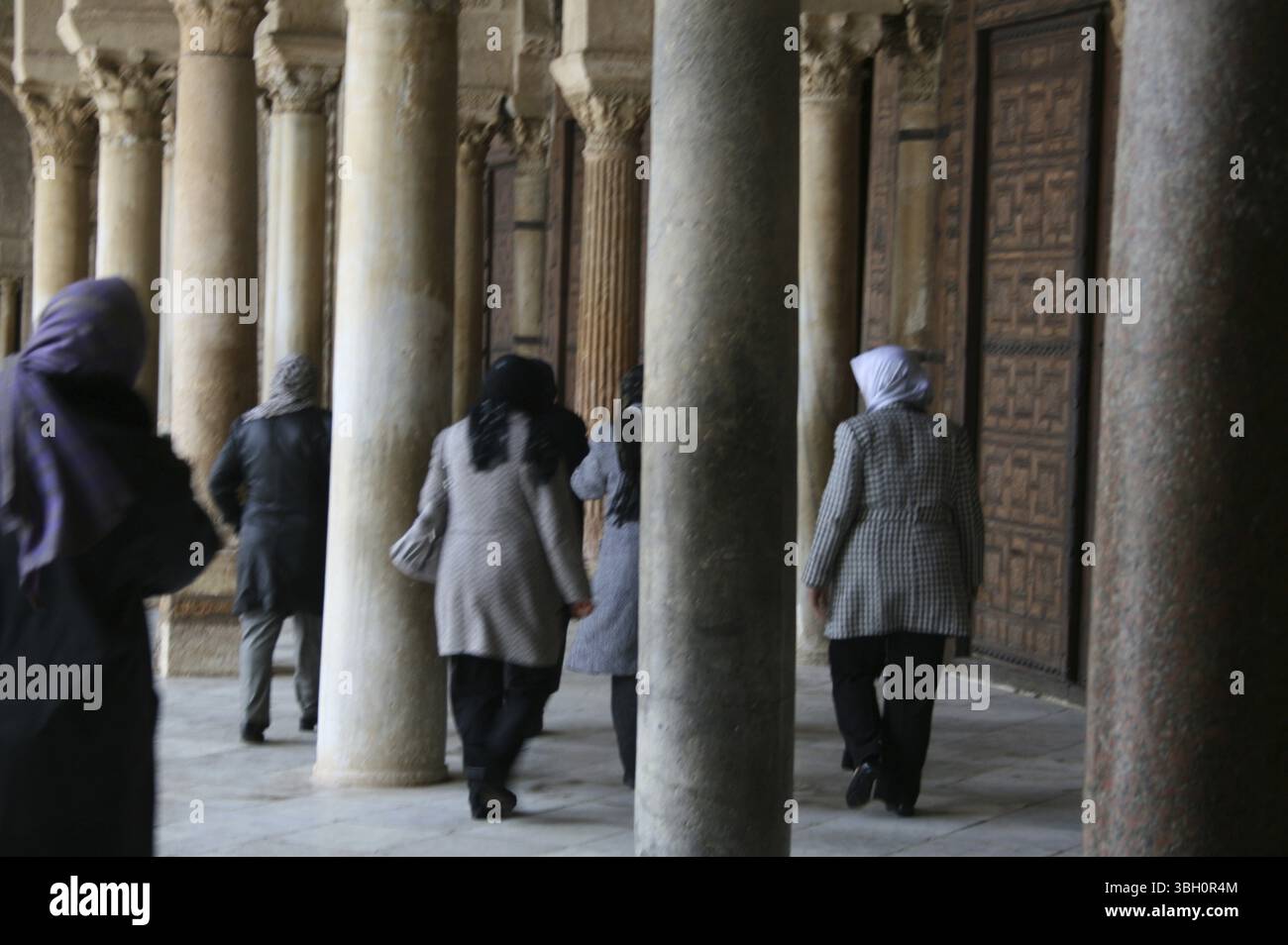 A group of people are walking through a column-lined courtyard, Tunisia ...
