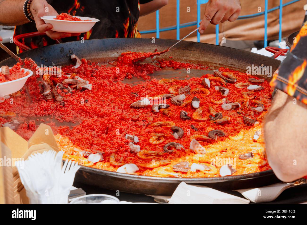 Cooked red rice seafood paella with sliced octopus and shrimp in giant ...
