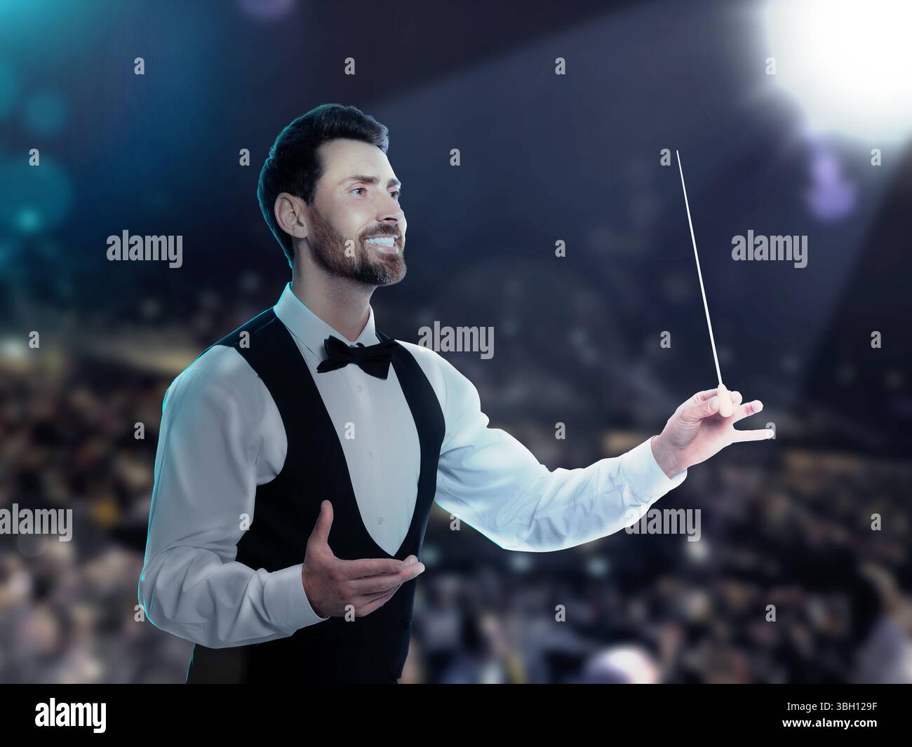 Conductor directing orchestra with baton on stage of concert hall Stock ...