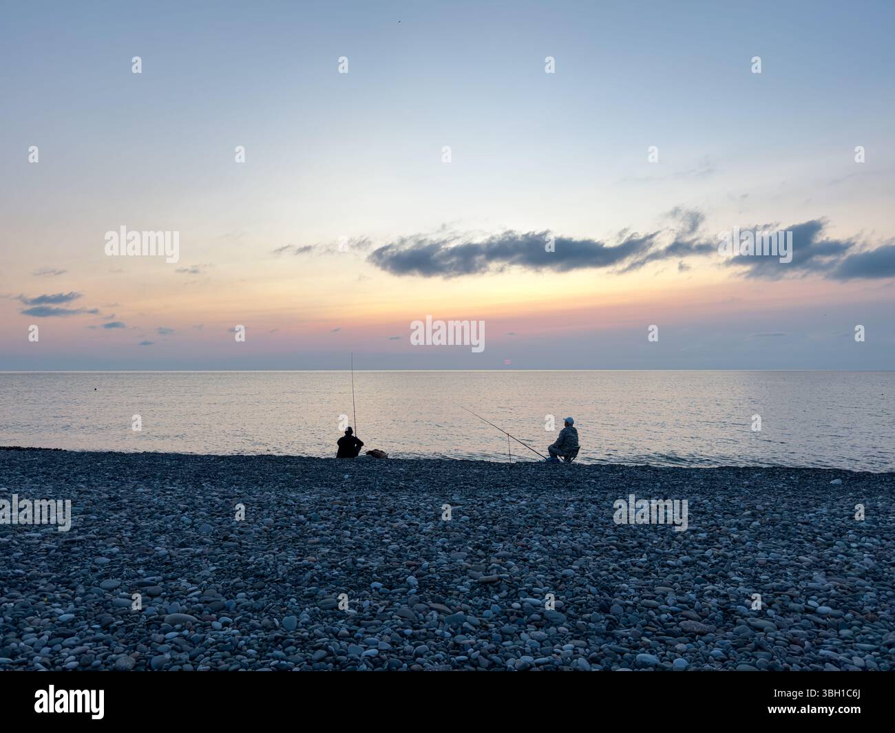 Two fishermen on pebble beach at Black Sea sunset, Batumi, Georgia ...