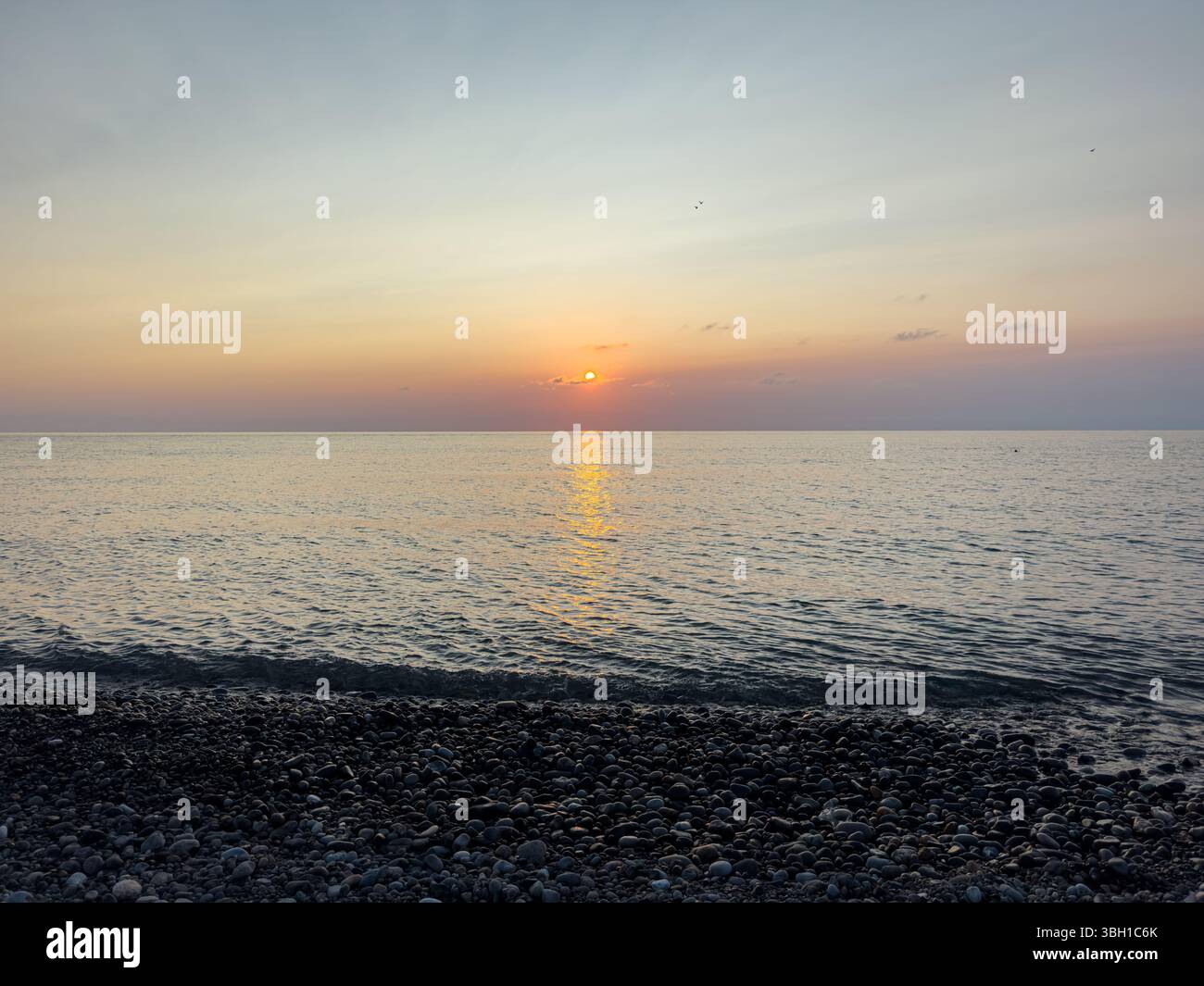 Black Sea sunset with pebble beach and calm waves in Batumi, Georgia ...