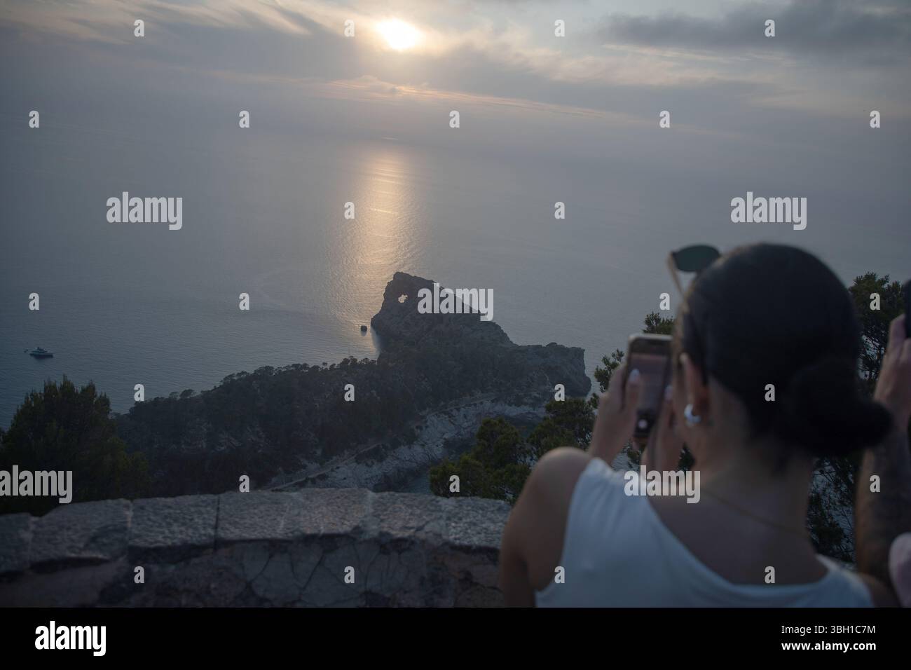 Deia, Spain. 06th June, 2025. A woman takes a photo of the sunset with ...