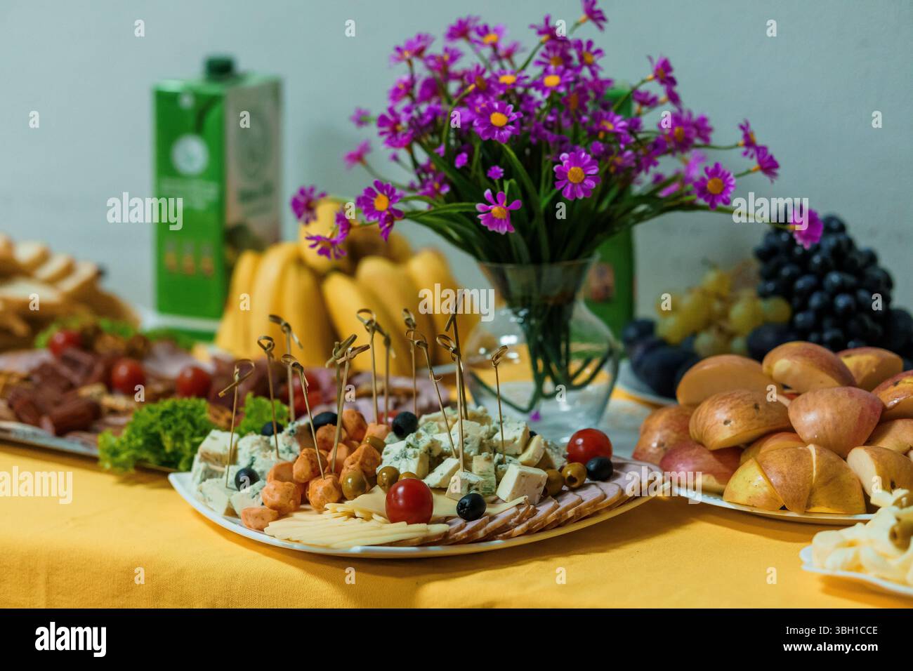 A vibrant still life showcases a cheese, fruit, and snack platter with ...