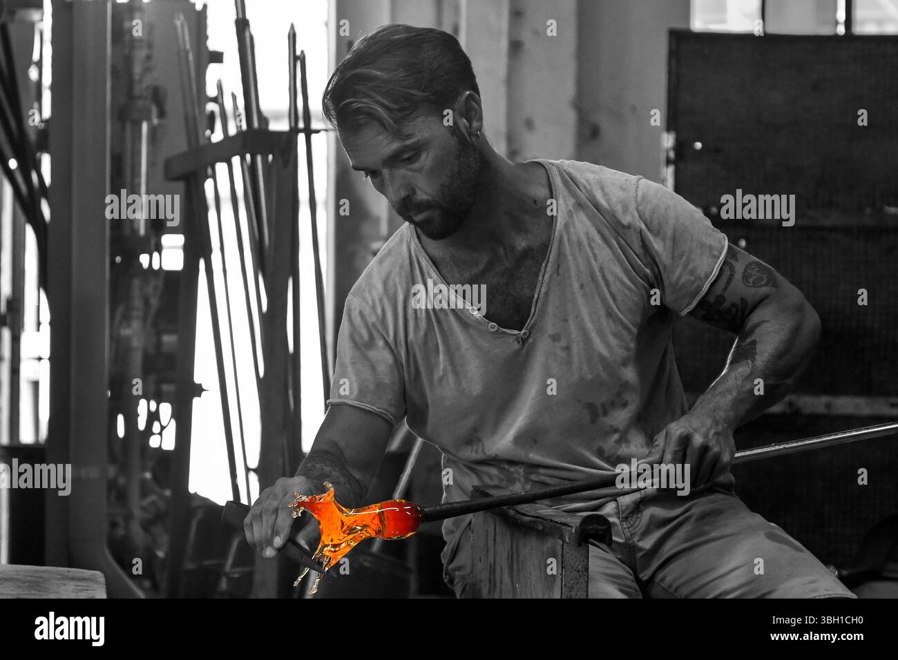 Selective color. A master glassmaker shaping a glass figurine in the ...