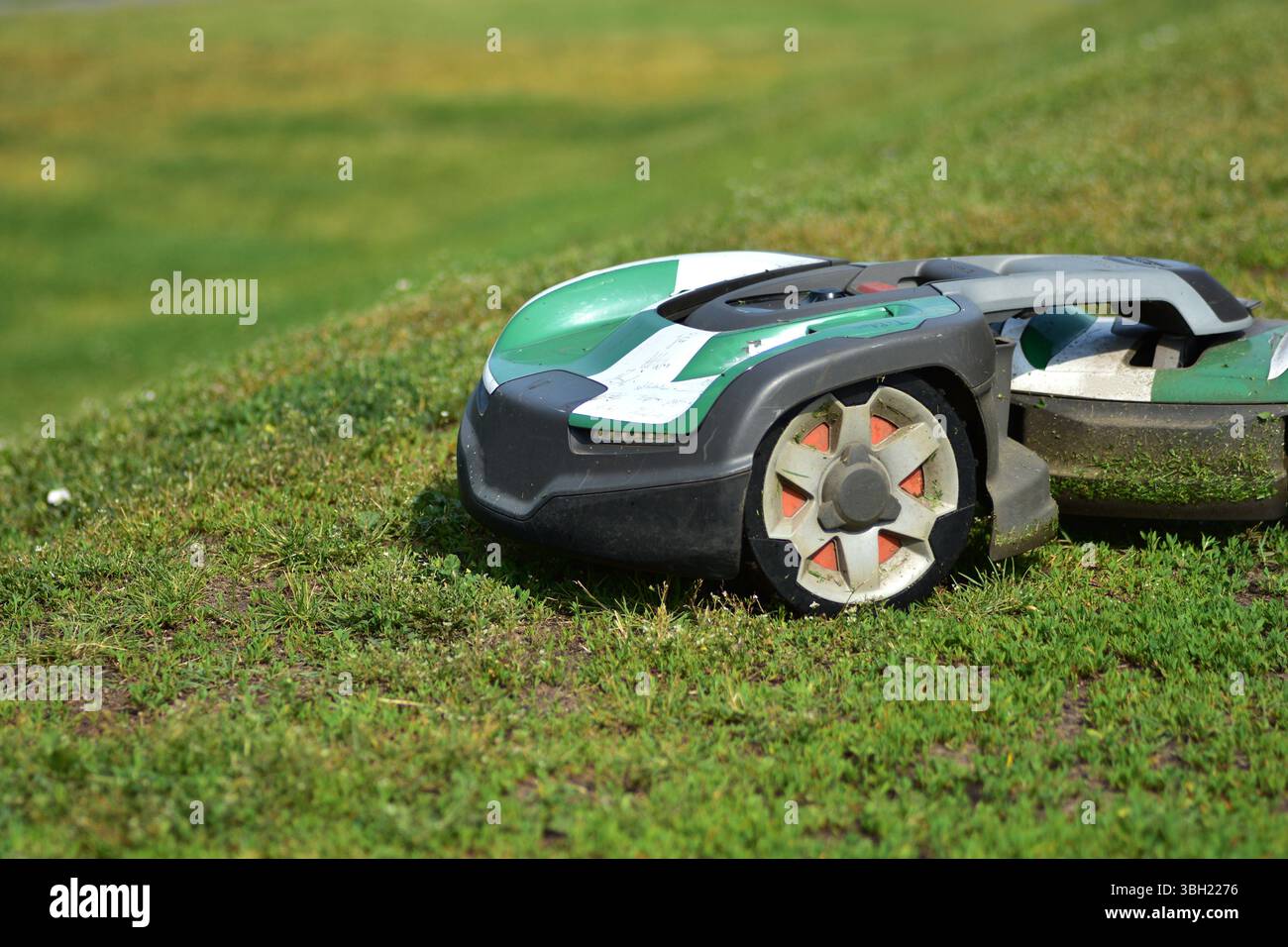 Autonomous robotic lawn mower working on a grassy hill. Smart garden ...