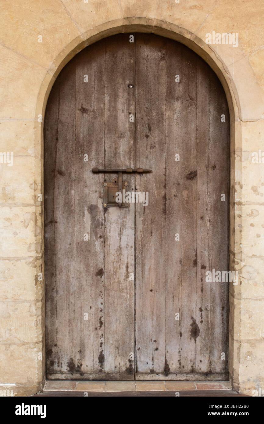 Rustic wood plank arched double doors leading into an old stone ...