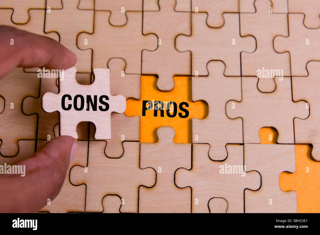 Hand places a wooden puzzle piece labeled cons next to a piece labeled ...