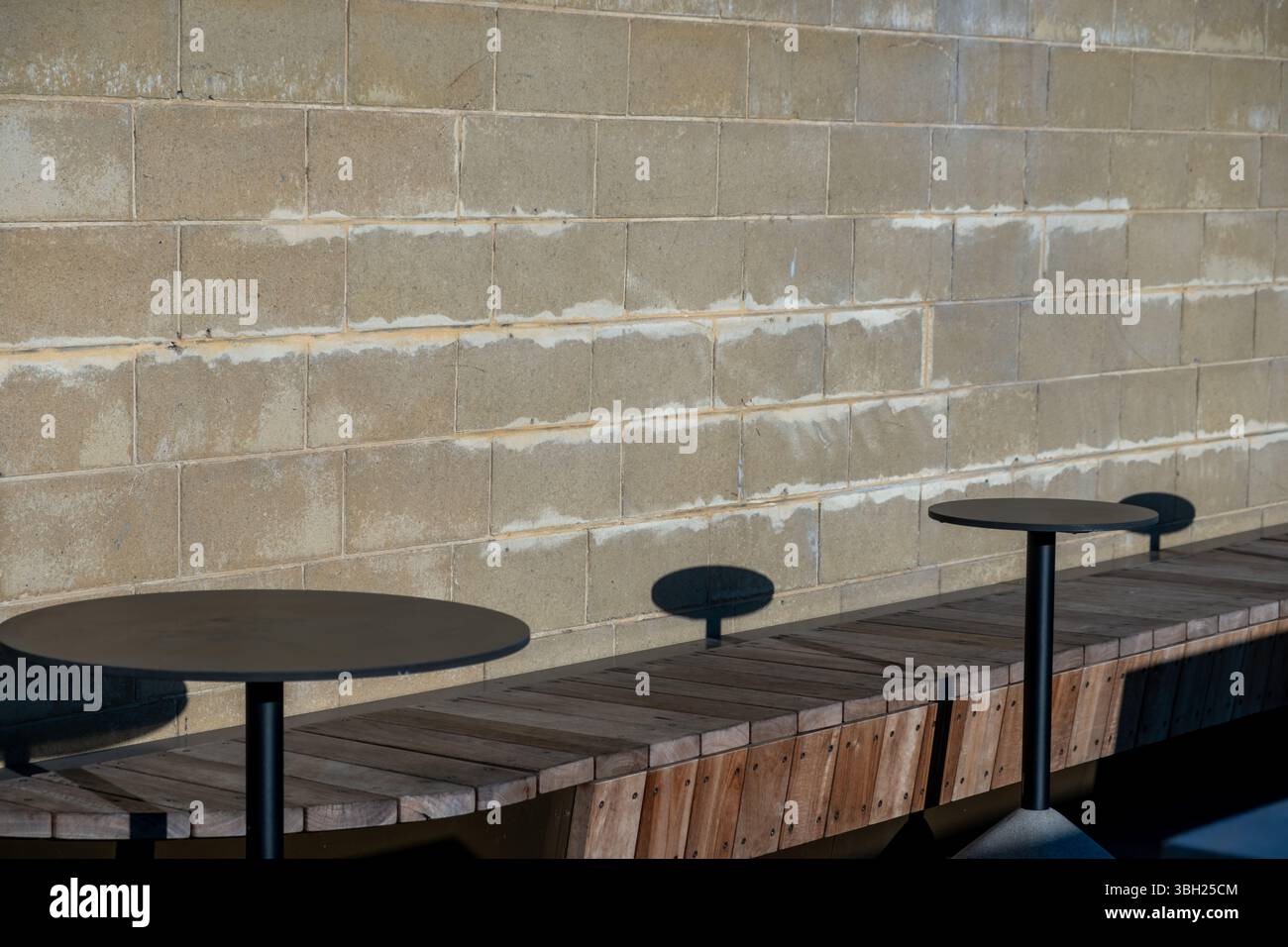 Wooden seating and metal tables next to the concrete wall Stock Photo ...
