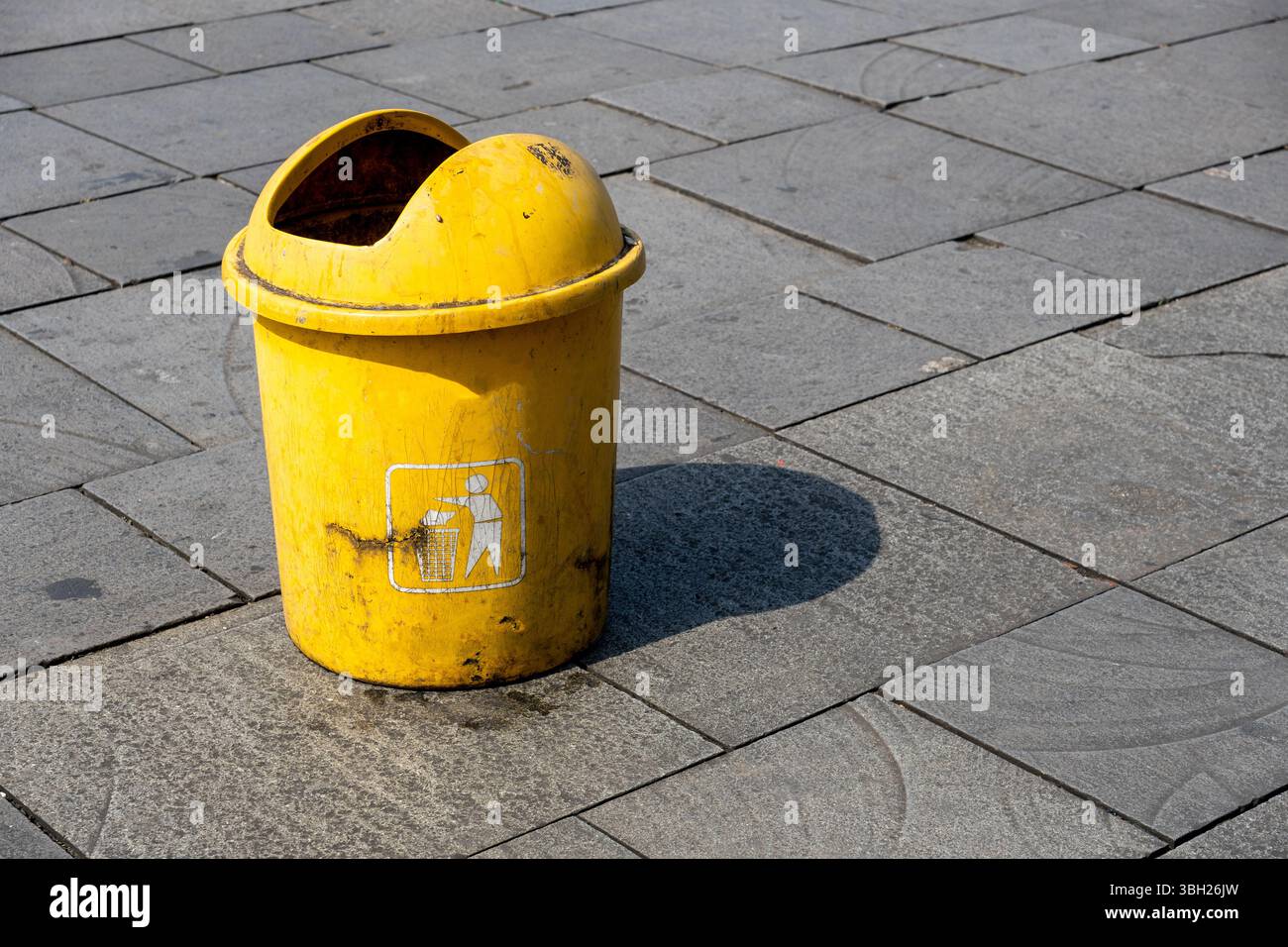 Yellow trash can is sitting on a gray tile floor. The trash can is ...