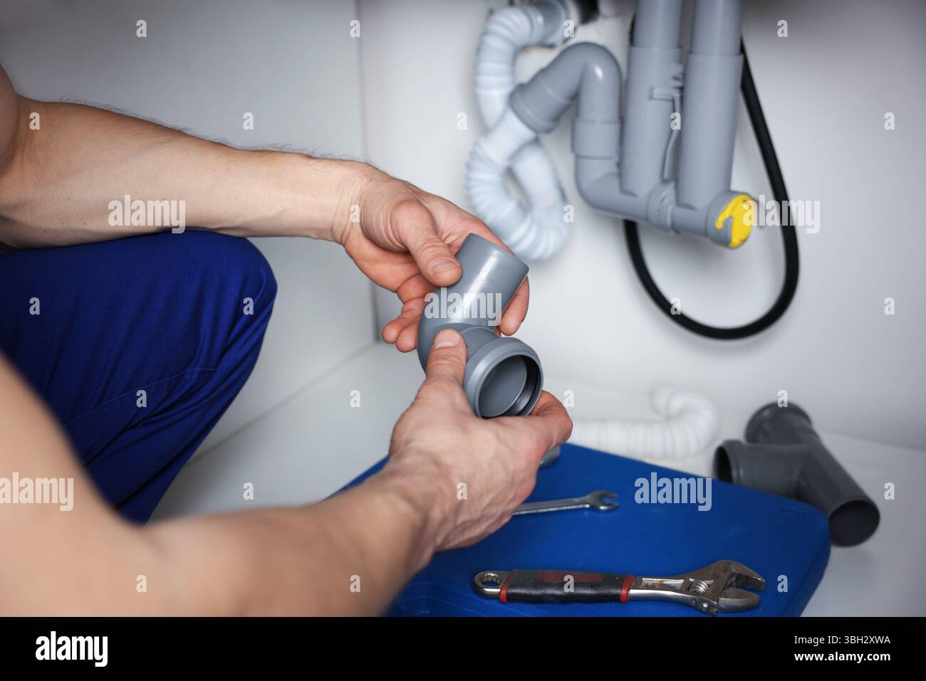 Plumber fixing pipes under sink indoors, closeup Stock Photo - Alamy