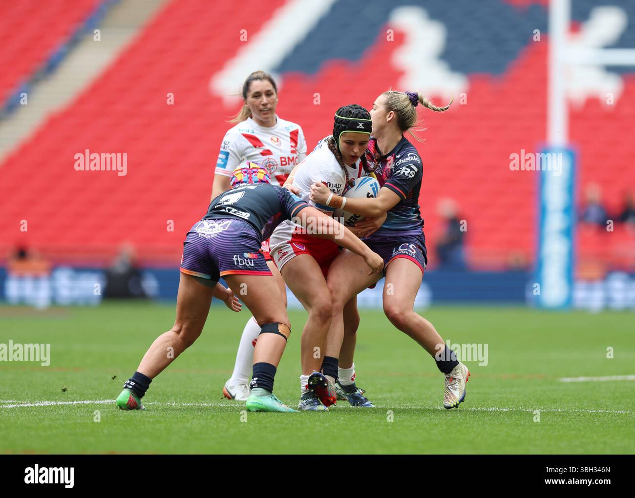 St Helens' Beri Salihi is tackled by Wigan Warriors' Isabel Rowe and ...