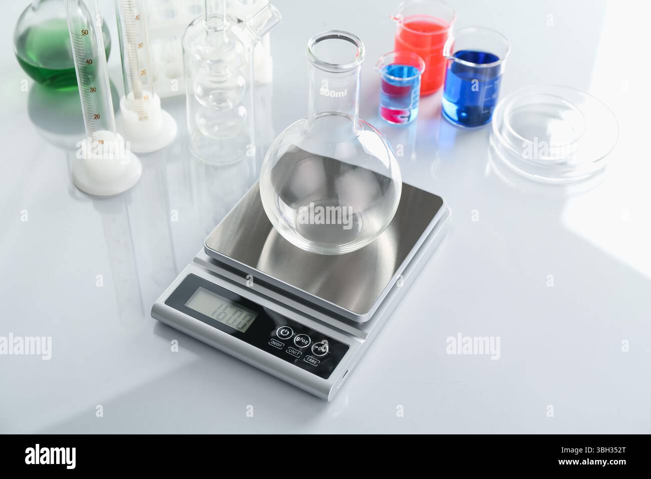Scale with empty flask and other laboratory glassware on white mirror ...