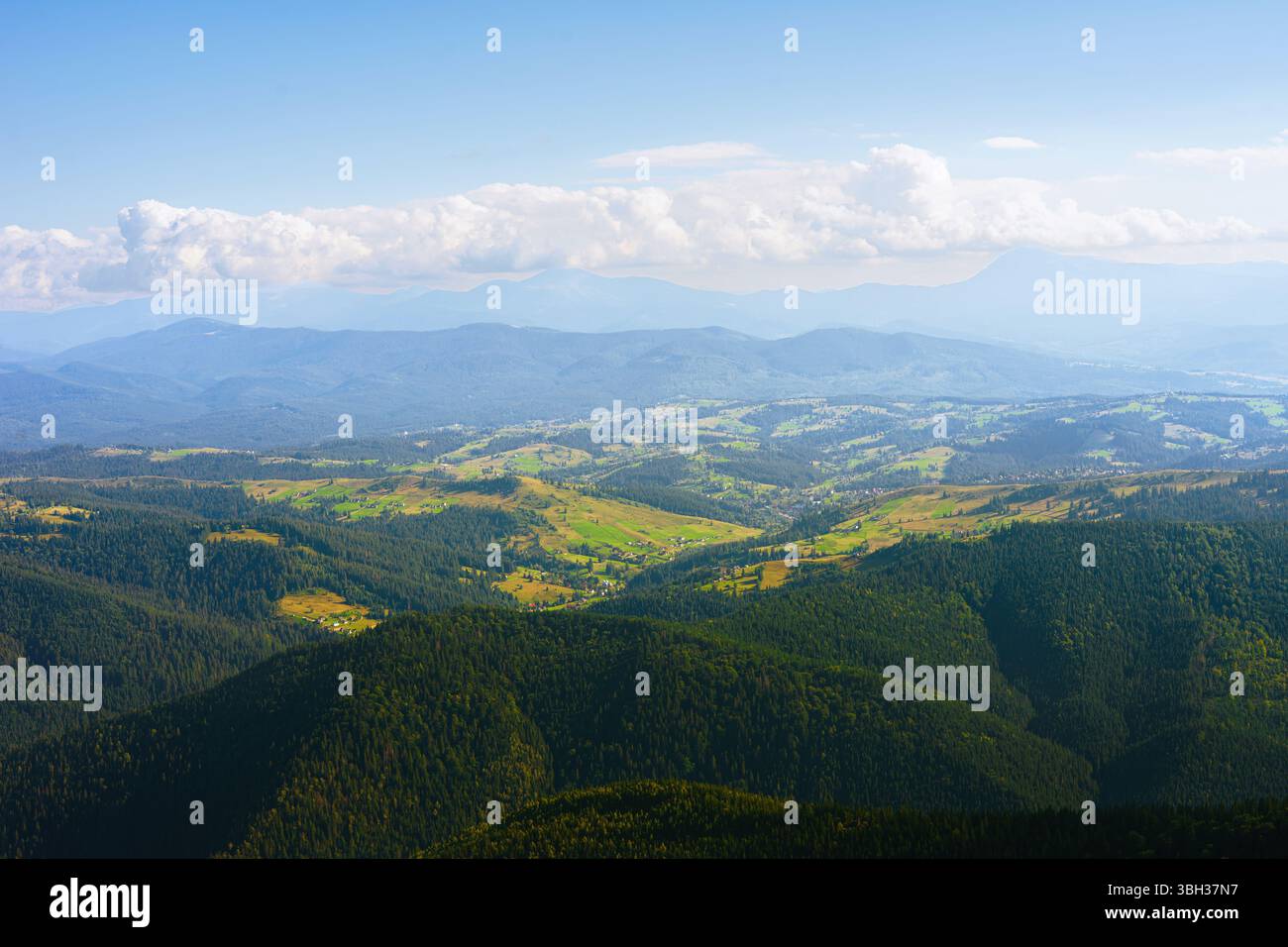 Atmospheric view of multiple mountain ridges covered with green ...