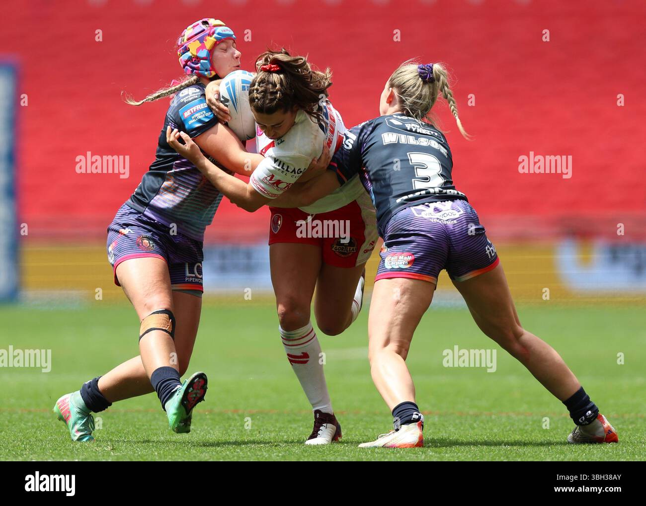 St Helens' Emily Rudge (centre) is tackled by Wigan Warriors' Isabel ...