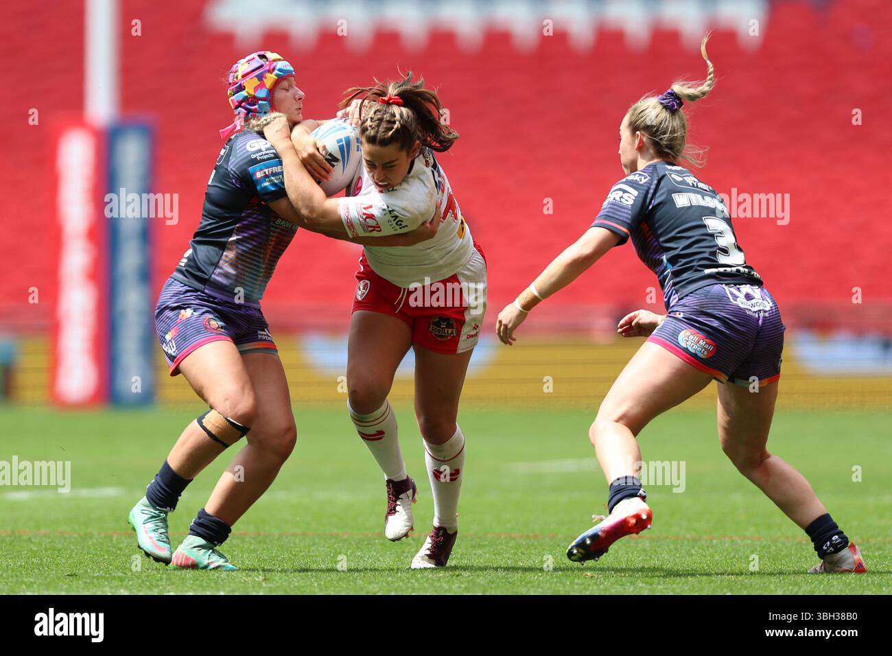 St Helens' Emily Rudge (centre) is tackled by Wigan Warriors' Isabel ...